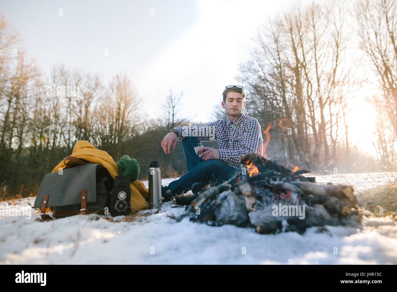 Handsome caucasian scout man warming his hands from bonfire in the ...