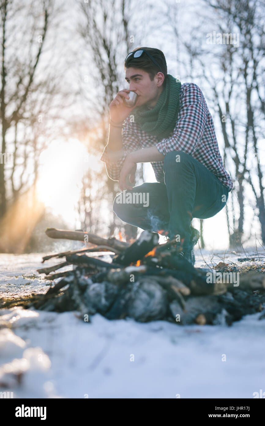 Handsome caucasian scout man warming his hands from bonfire in the ...