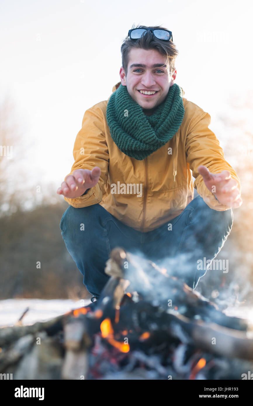 Handsome caucasian scout man warming his hands from bonfire in the ...
