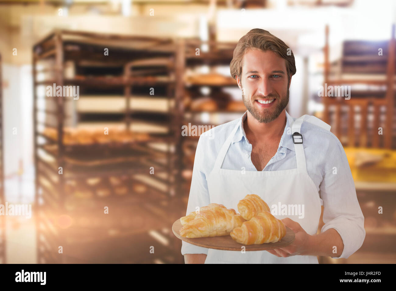 Waiter holding croissant on a tray against baking trolley in bakery ...