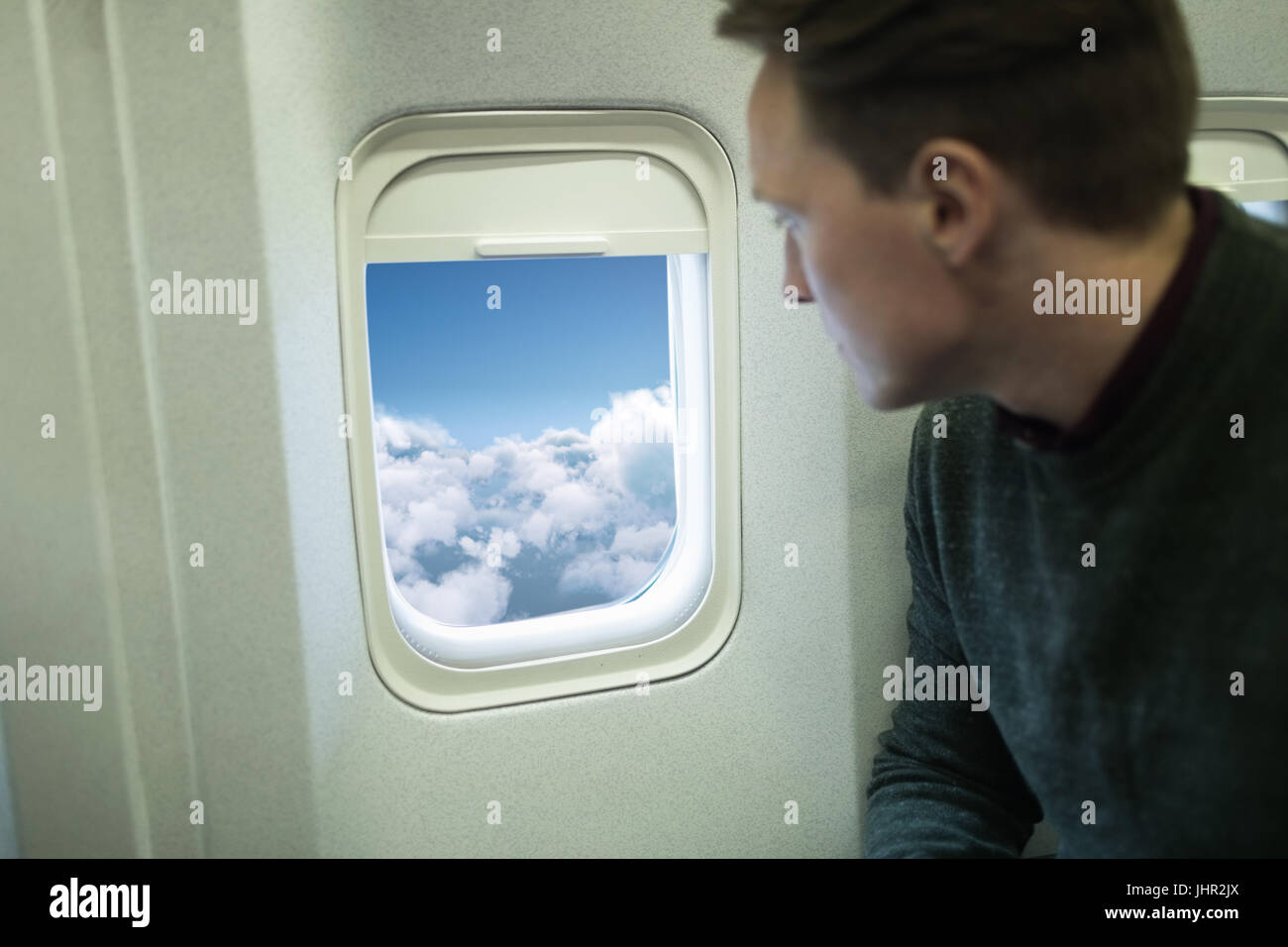 Male passenger looking through window while travelling in an aircraft ...