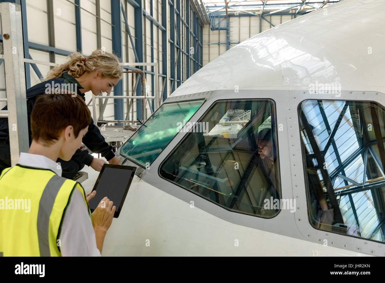 Aircraft maintenance engineers working over cockpit of an aircraft at ...