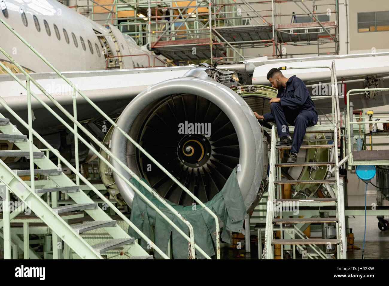 Aircraft maintenance engineer examining turbine engine of aircraft at ...