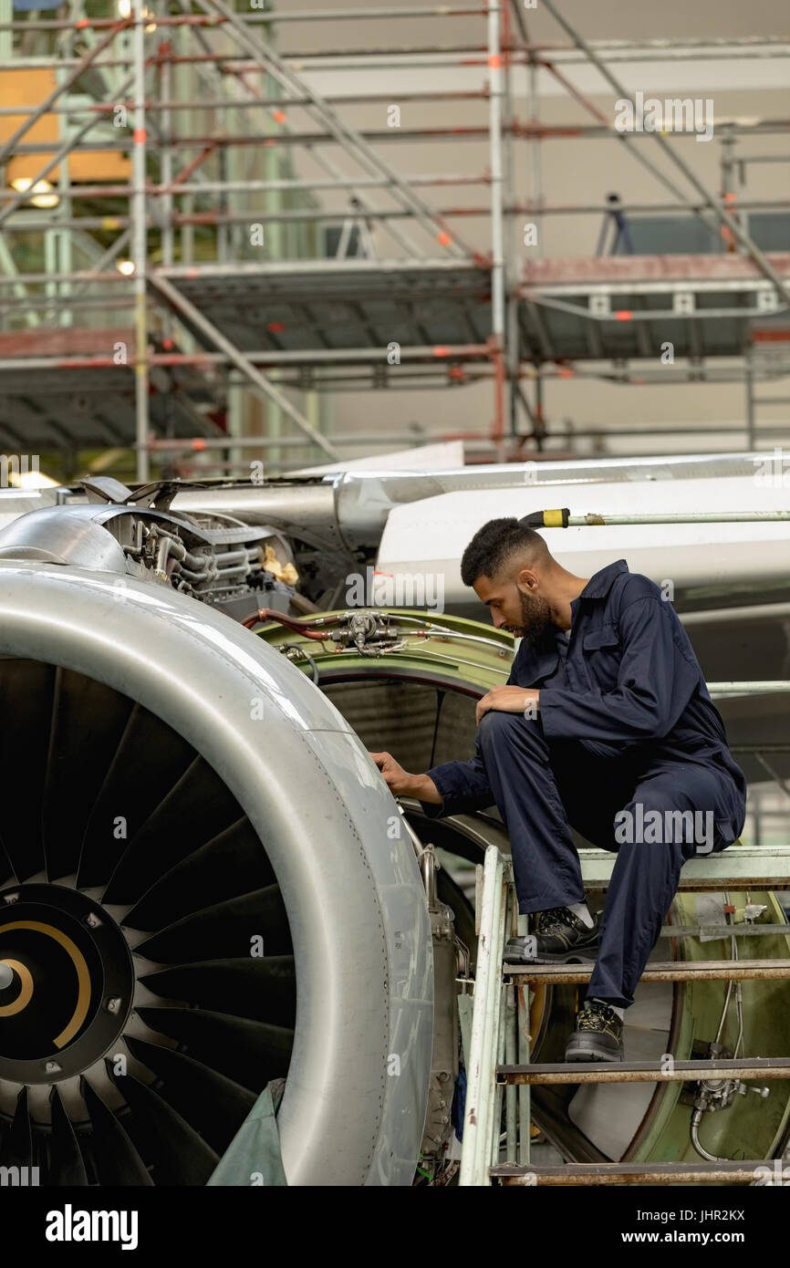 Aircraft maintenance engineer examining turbine engine of aircraft at ...