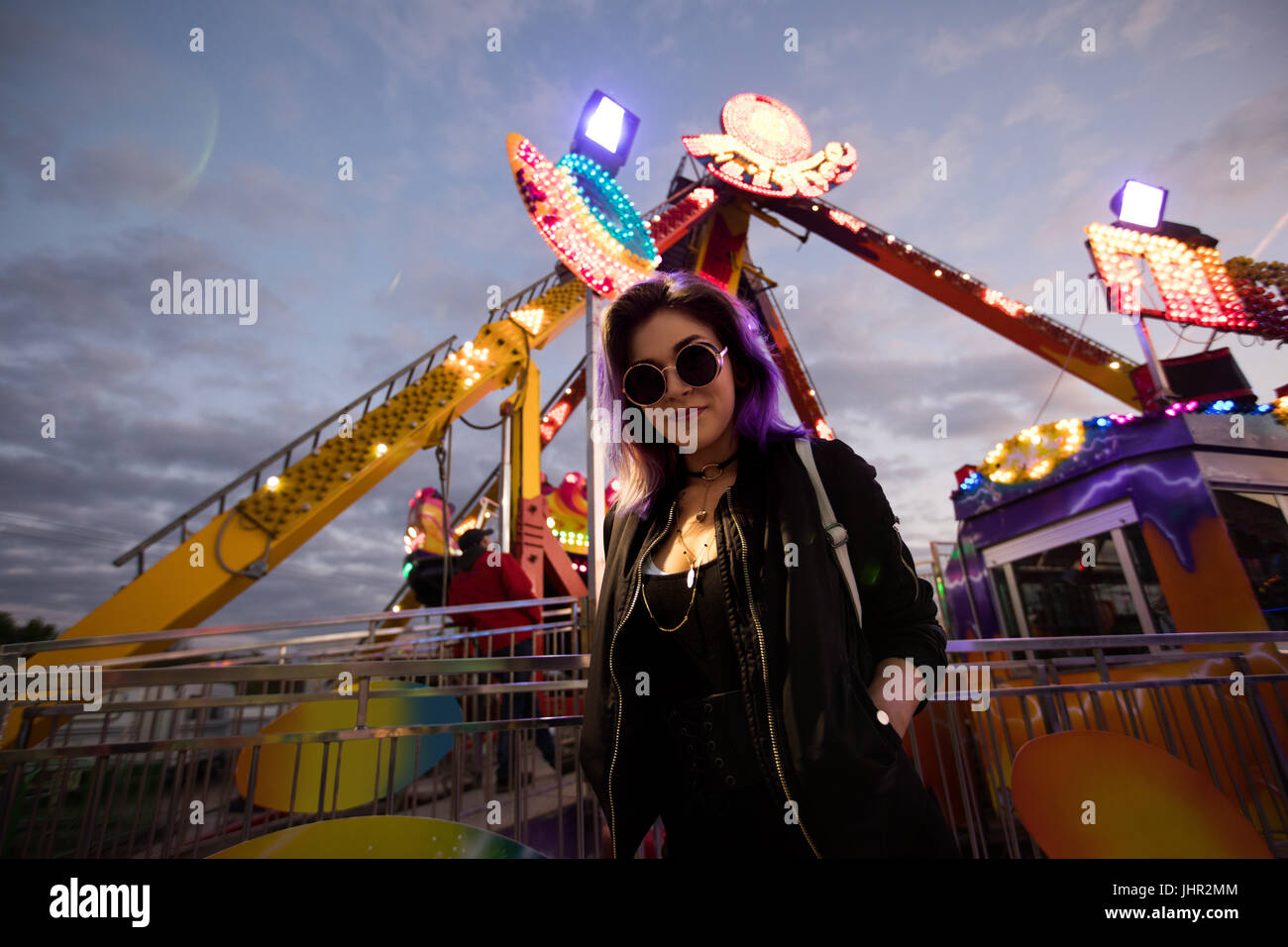 Beautiful woman standing against pendulum rides in amusement park at ...