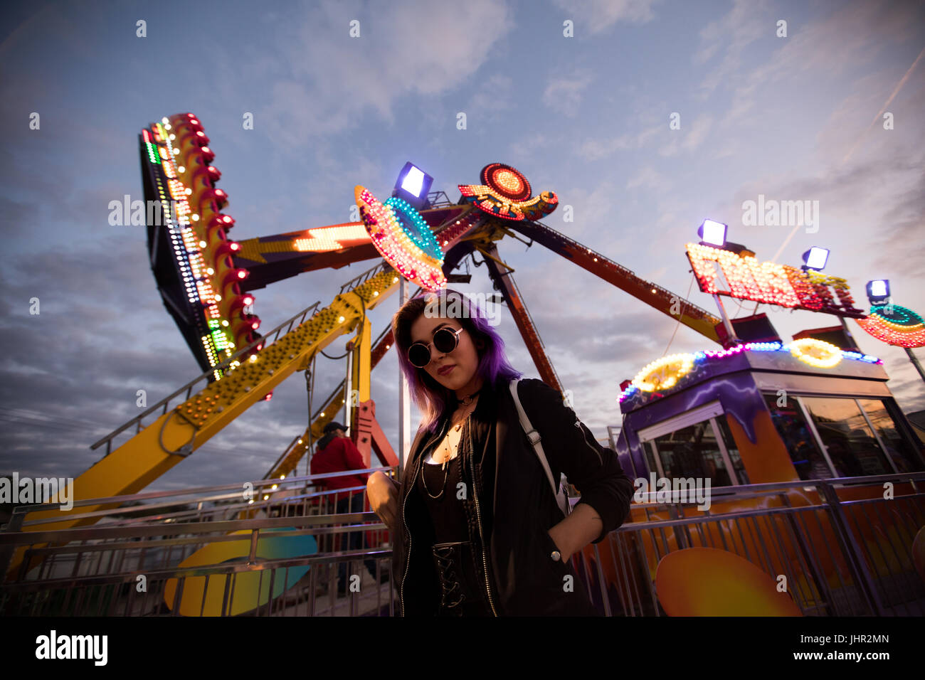 Beautiful woman standing against pendulum rides in amusement park at ...