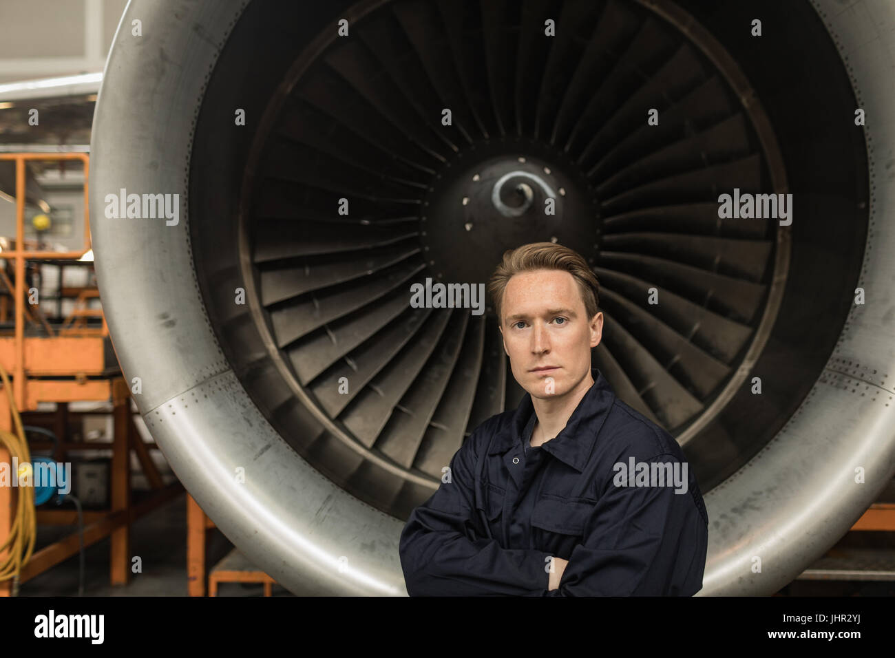 Portrait of male aircraft maintenance engineer standing with arms ...
