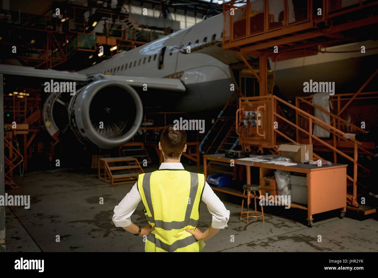 Rear view of female aircraft maintenance engineer standing at airlines ...