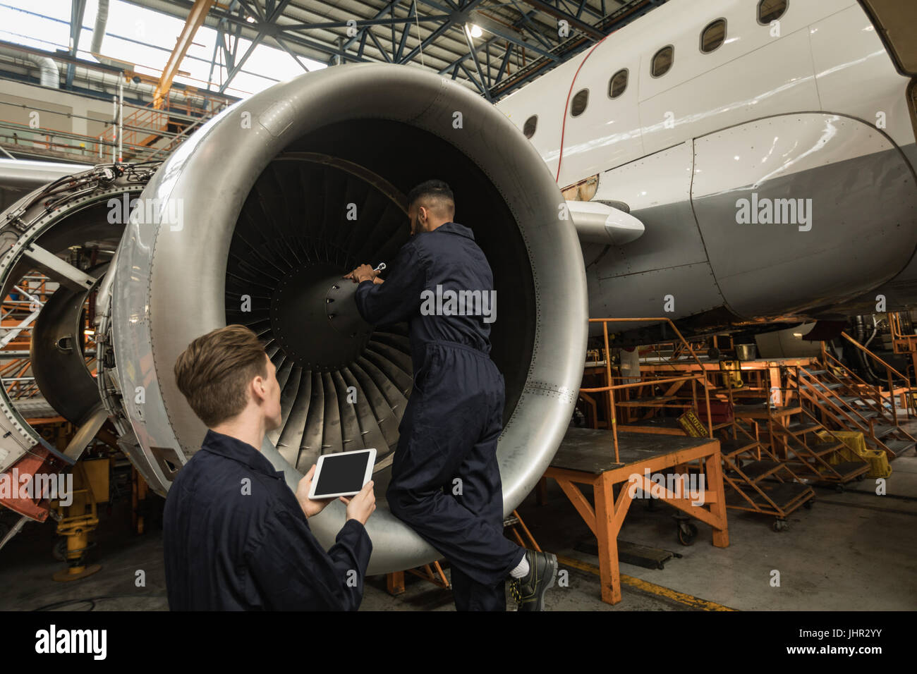 Aircraft maintenance engineers examining turbine engine of aircraft at ...