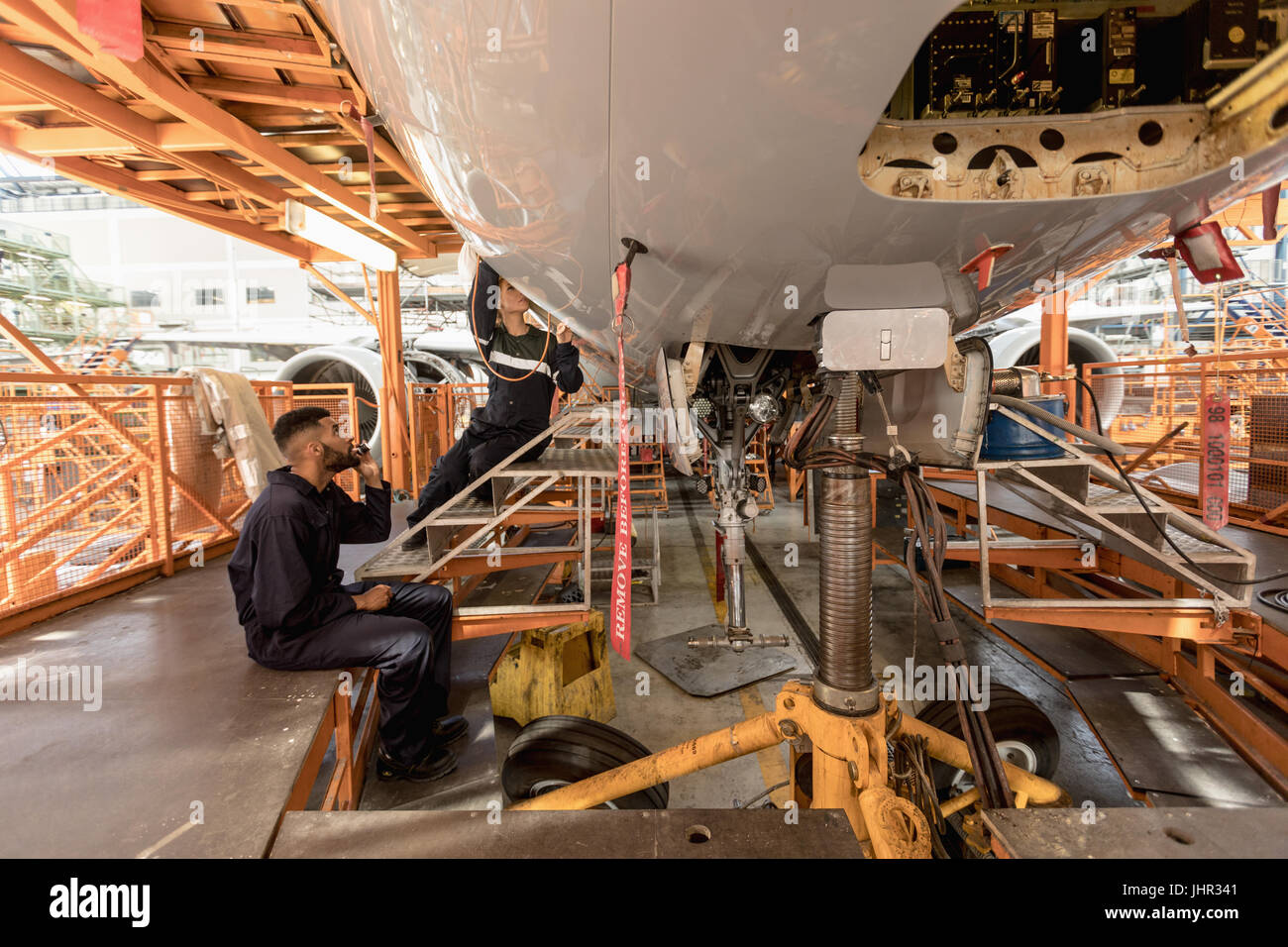 Male aircraft maintenance engineers working over an aircraft engine at ...