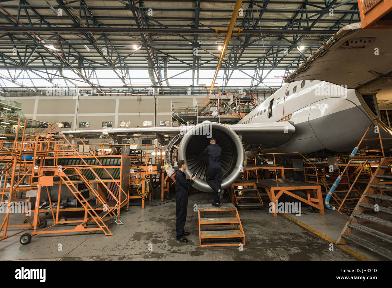 Aircraft maintenance engineers examining turbine engine of aircraft at ...