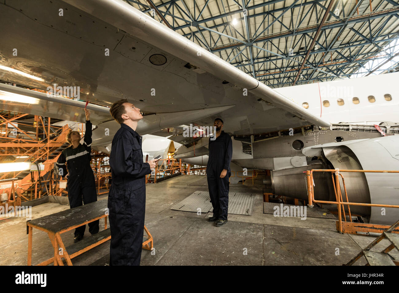 Aircraft maintenance engineers examining aircraft wing at airlines ...