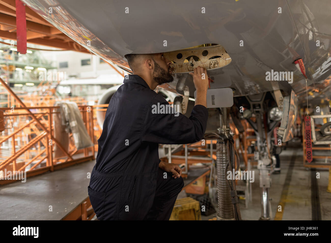 Male aircraft maintenance engineers working over an aircraft engine at airlines maintenance ...