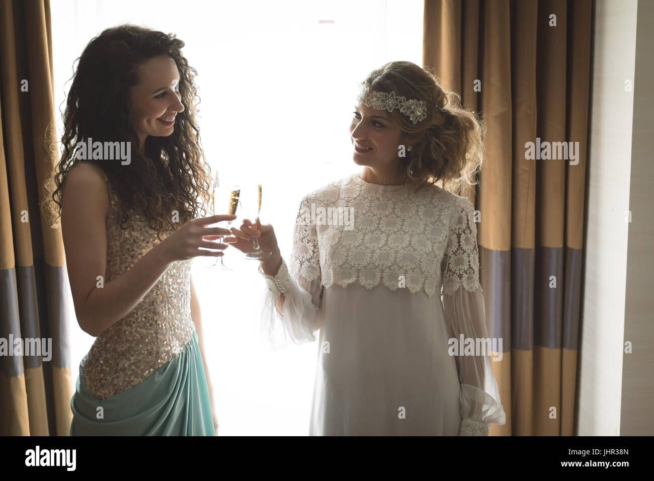 Bride and bridesmaid toasting a glasses of champagne at home Stock ...
