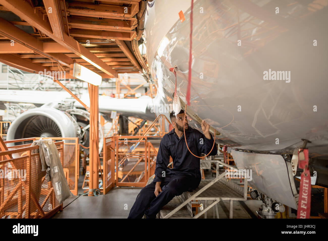 Male aircraft maintenance engineers working over an aircraft engine at airlines maintenance ...