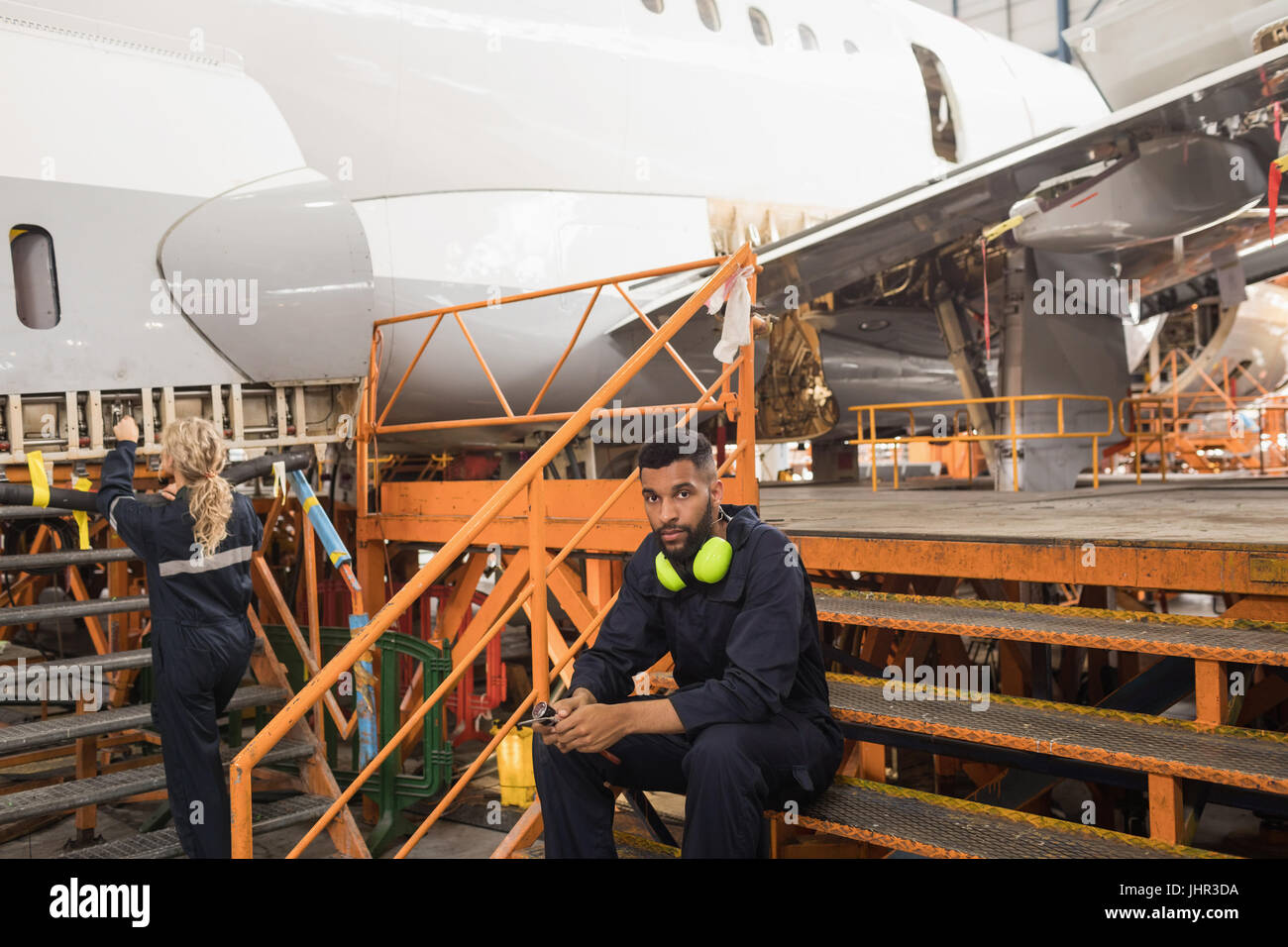 Female aircraft maintenance engineers working over an aircraft while ...