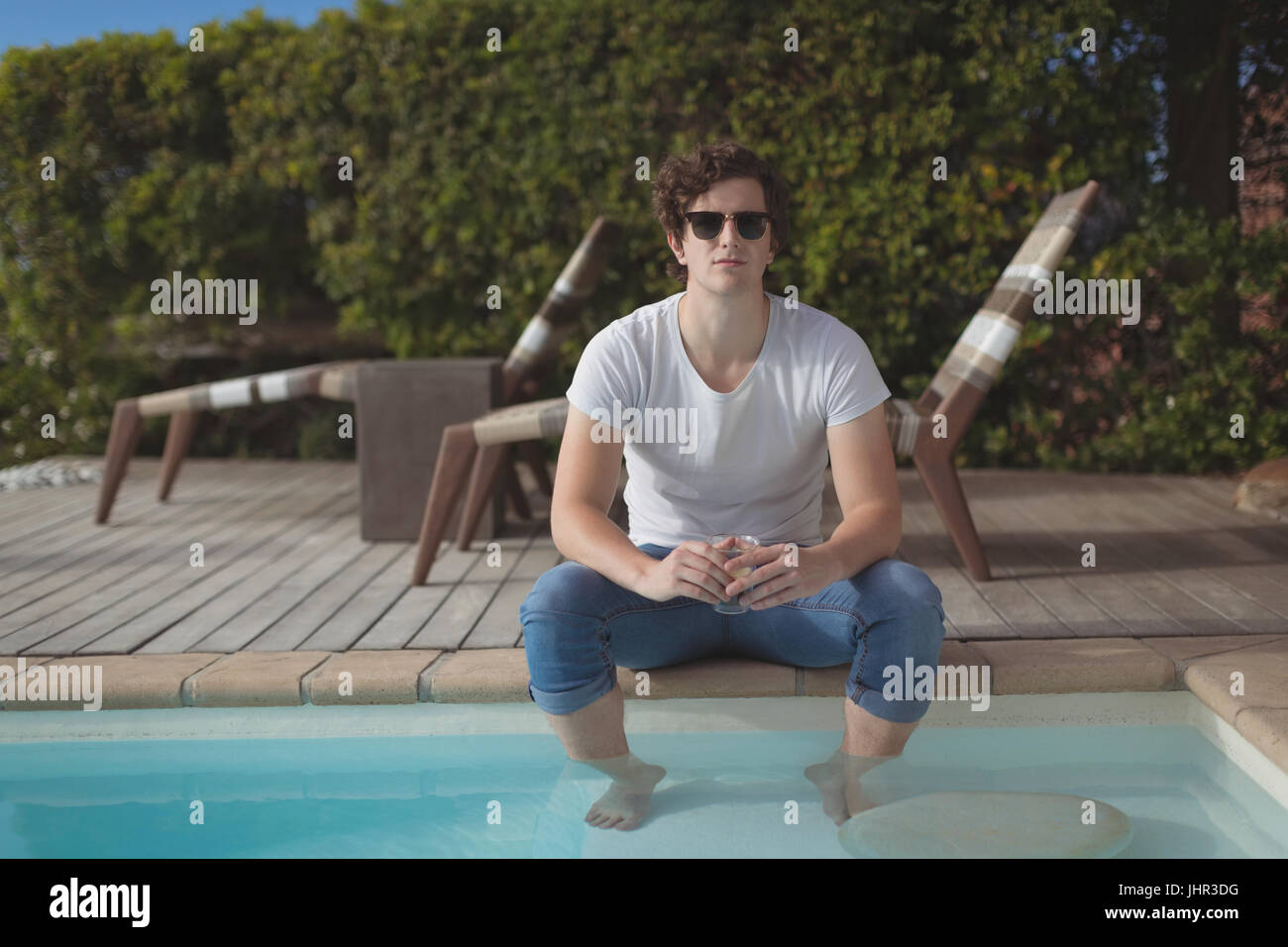 Handsome man sitting near pool side on a sunny day at home Stock Photo ...