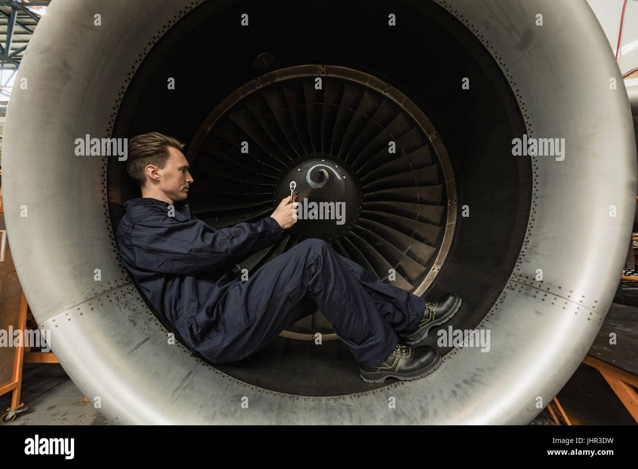 Male aircraft maintenance engineer fixing turbine blade of aircraft at airlines maintenance ...