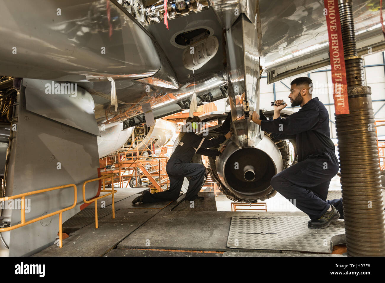 Aircraft maintenance engineers examining turbine engine of aircraft at ...