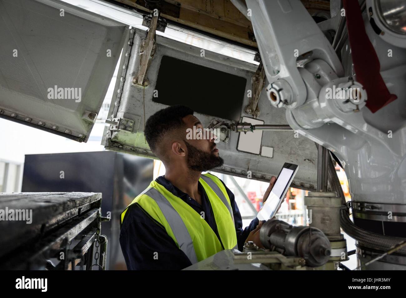 Male aircraft maintenance engineer examining engine of airplane at airlines maintenance facility ...