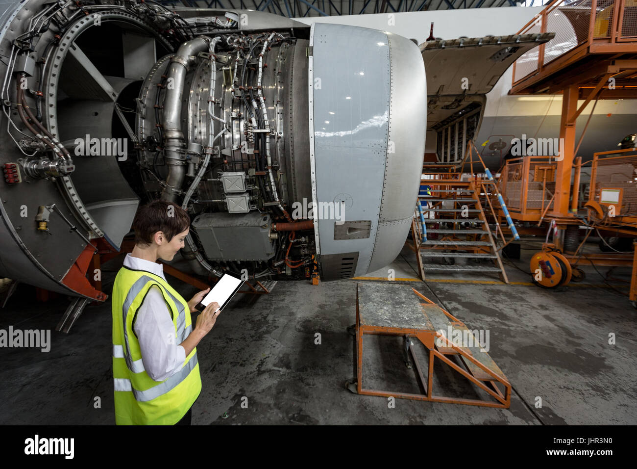 Female aircraft maintenance engineer examining turbine engine of ...