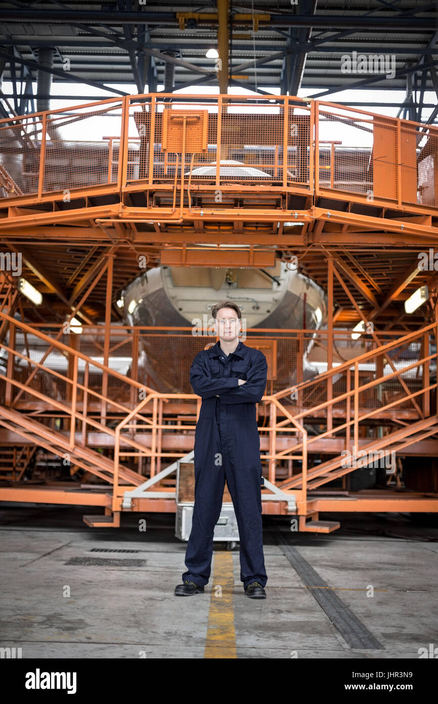 Portrait of female aircraft maintenance engineer standing with arms ...