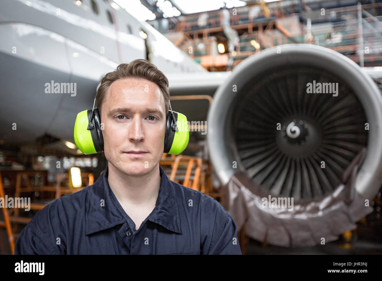 Portrait of male aircraft maintenance engineer standing at airlines ...