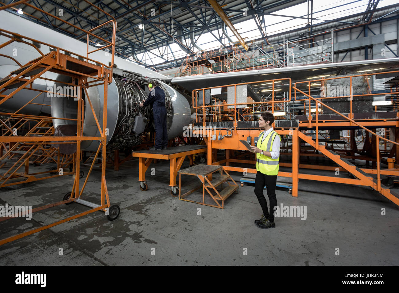 Male aircraft maintenance engineers examining turbine engine of ...