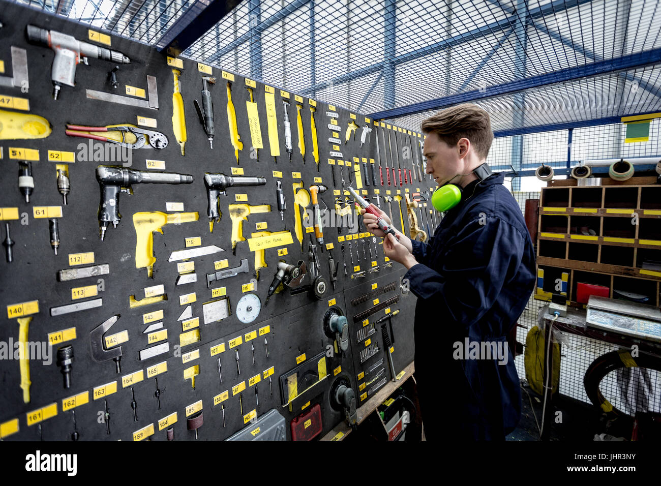 Male aircraft maintenance engineer examining various work tool at airlines maintenance facility ...