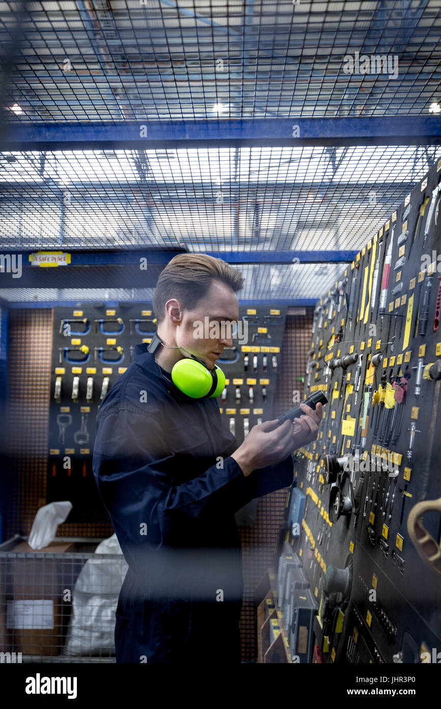 Male aircraft maintenance engineer examining various work tool at airlines maintenance facility ...