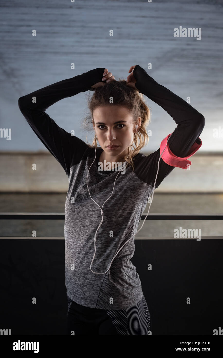 Portrait of fit woman tying her hair in fitness studio Stock Photo - Alamy