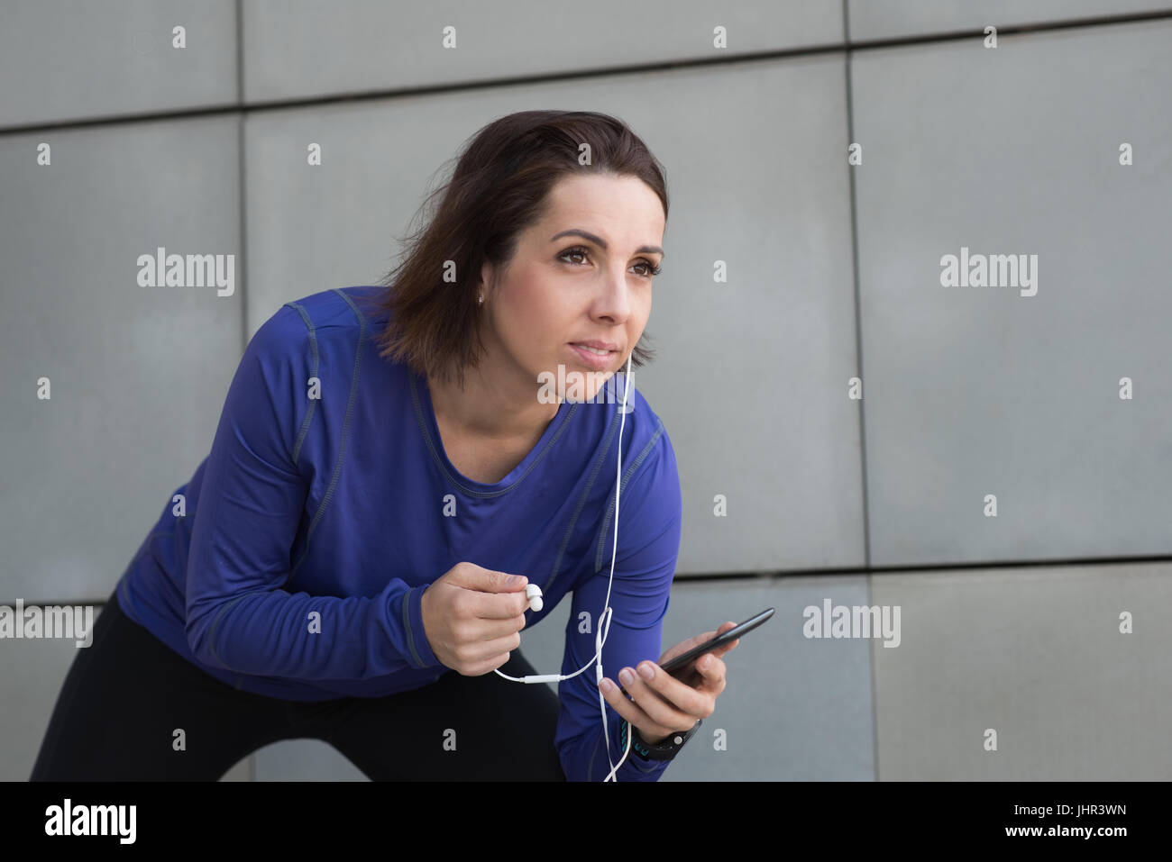 Fit woman using mobile phone while performing stretching exercise ...