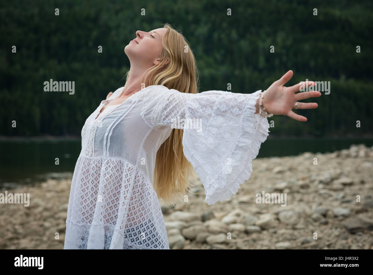 Side view of woman standing with arms outstretched at lakeshore Stock ...