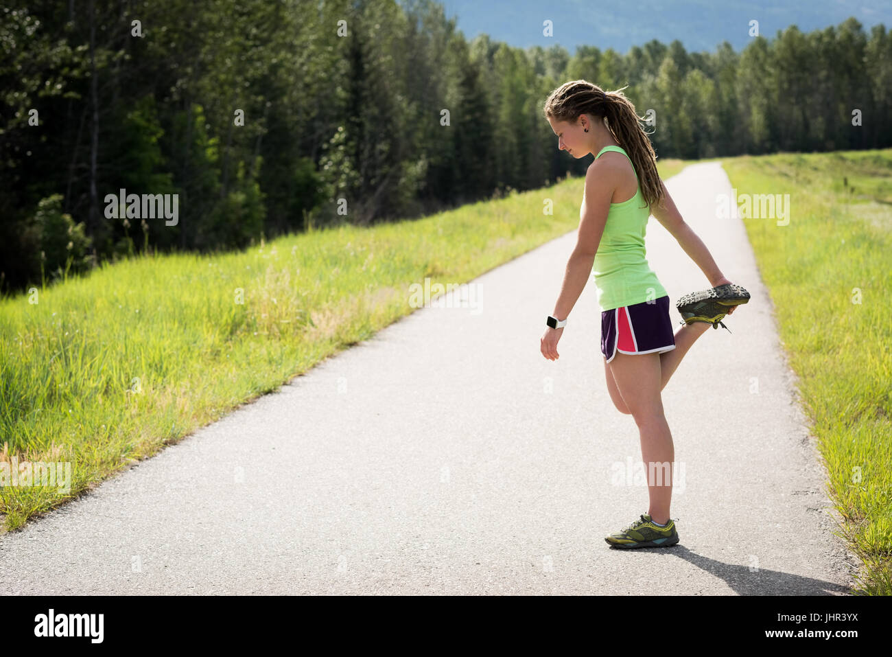 Side view of woman stretching leg on footpath Stock Photo - Alamy