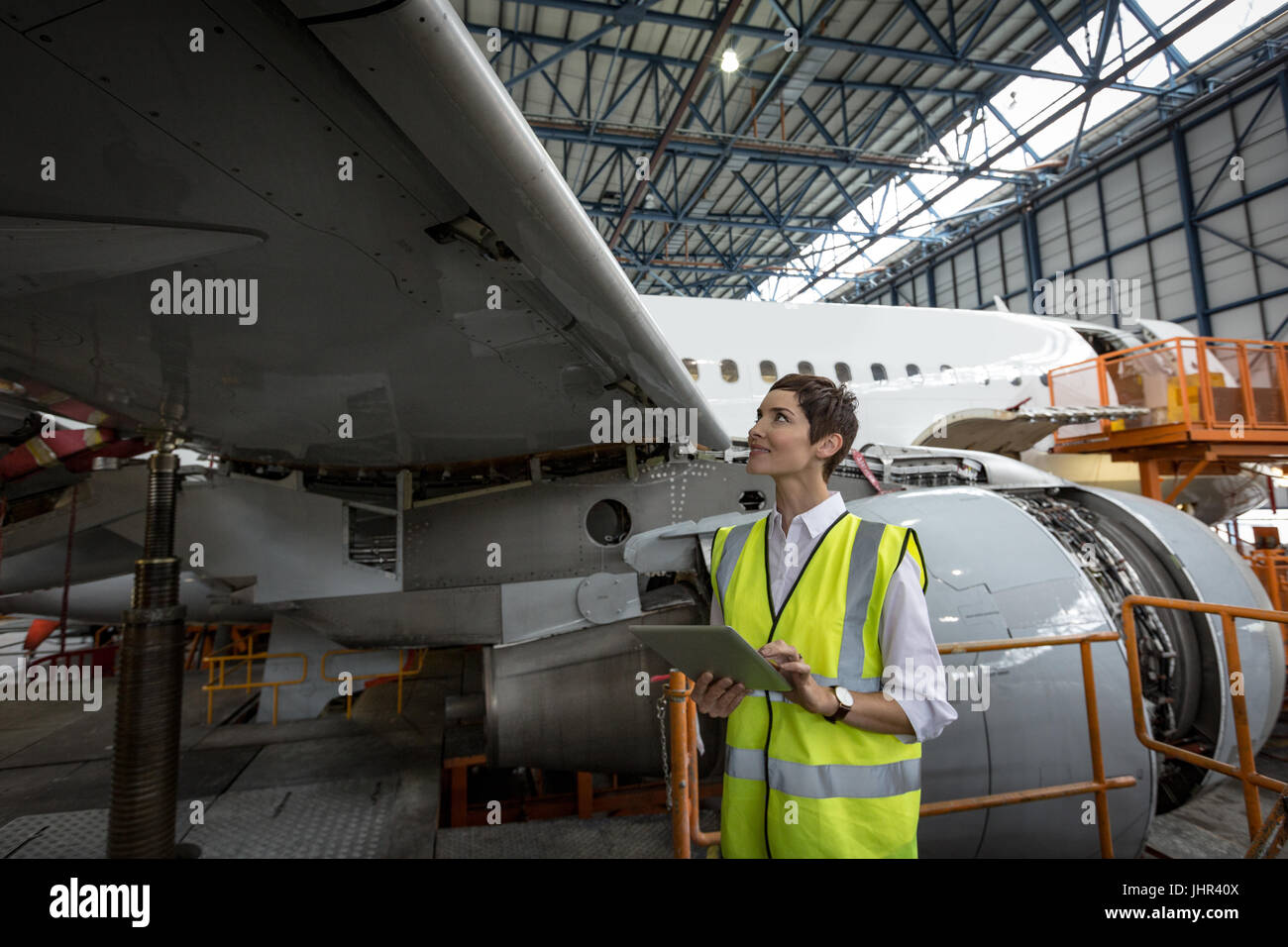 Female aircraft maintenance engineer examining engine of airplane at ...