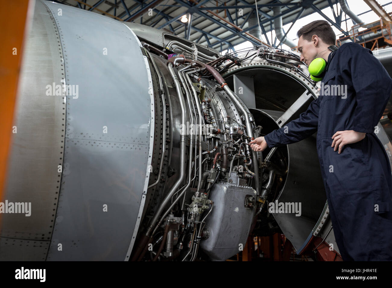 Male aircraft maintenance engineer examining turbine engine of aircraft at airlines maintenance ...