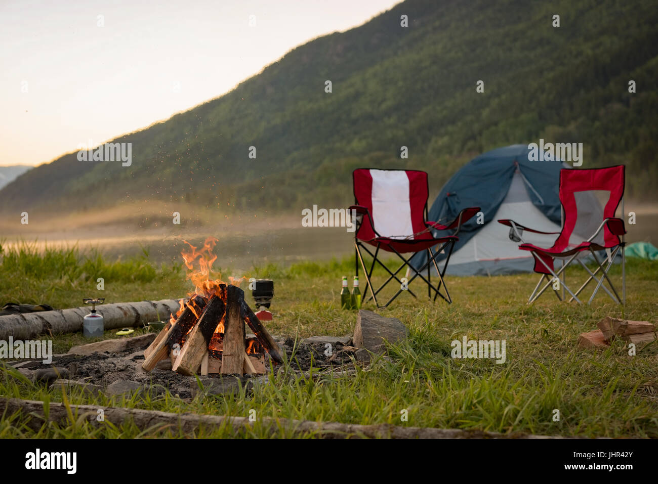 Empty camp chair with campfire at campsite Stock Photo - Alamy