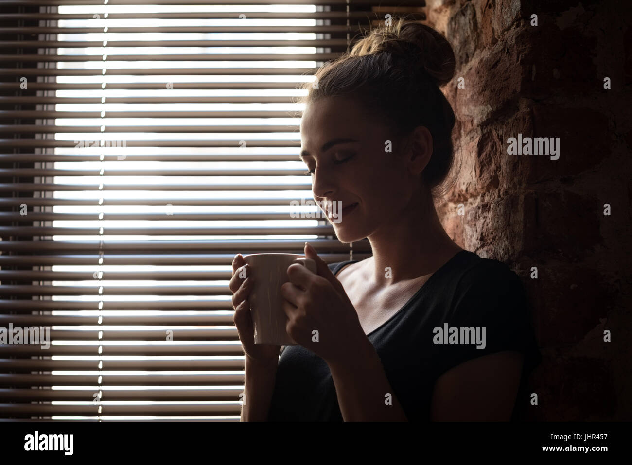 Beautiful woman having coffee near window at home Stock Photo - Alamy