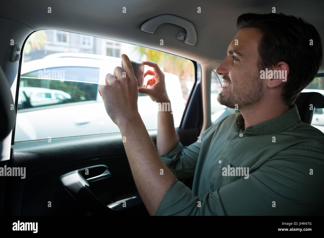 Smiling man clicking photograph on mobile phone from car window Stock ...