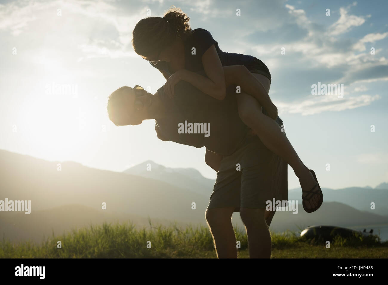 Man giving piggyback ride to his partner in countryside at dusk Stock ...