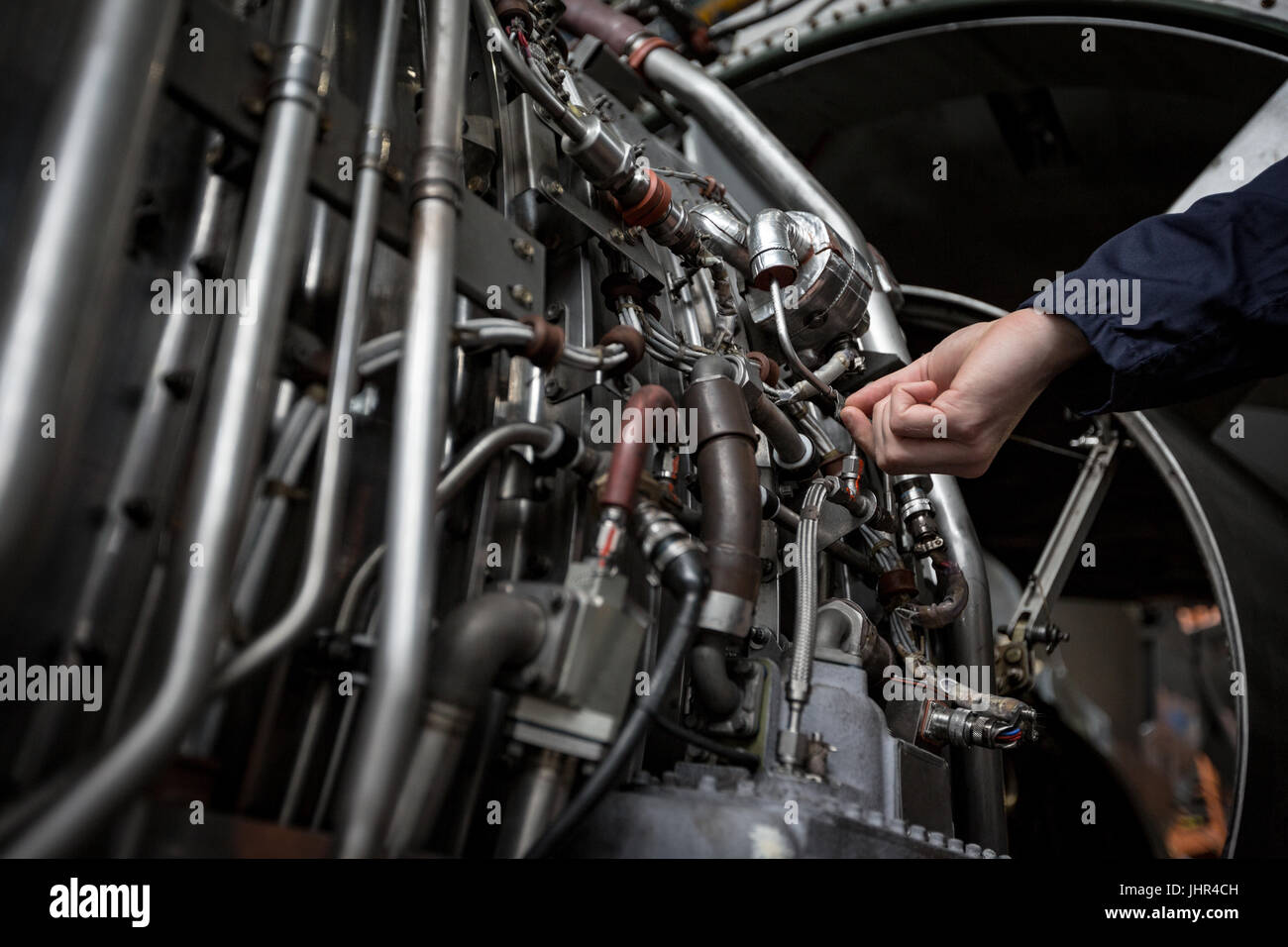 Close-up of male aircraft maintenance engineer examining turbine engine of aircraft at airlines ...