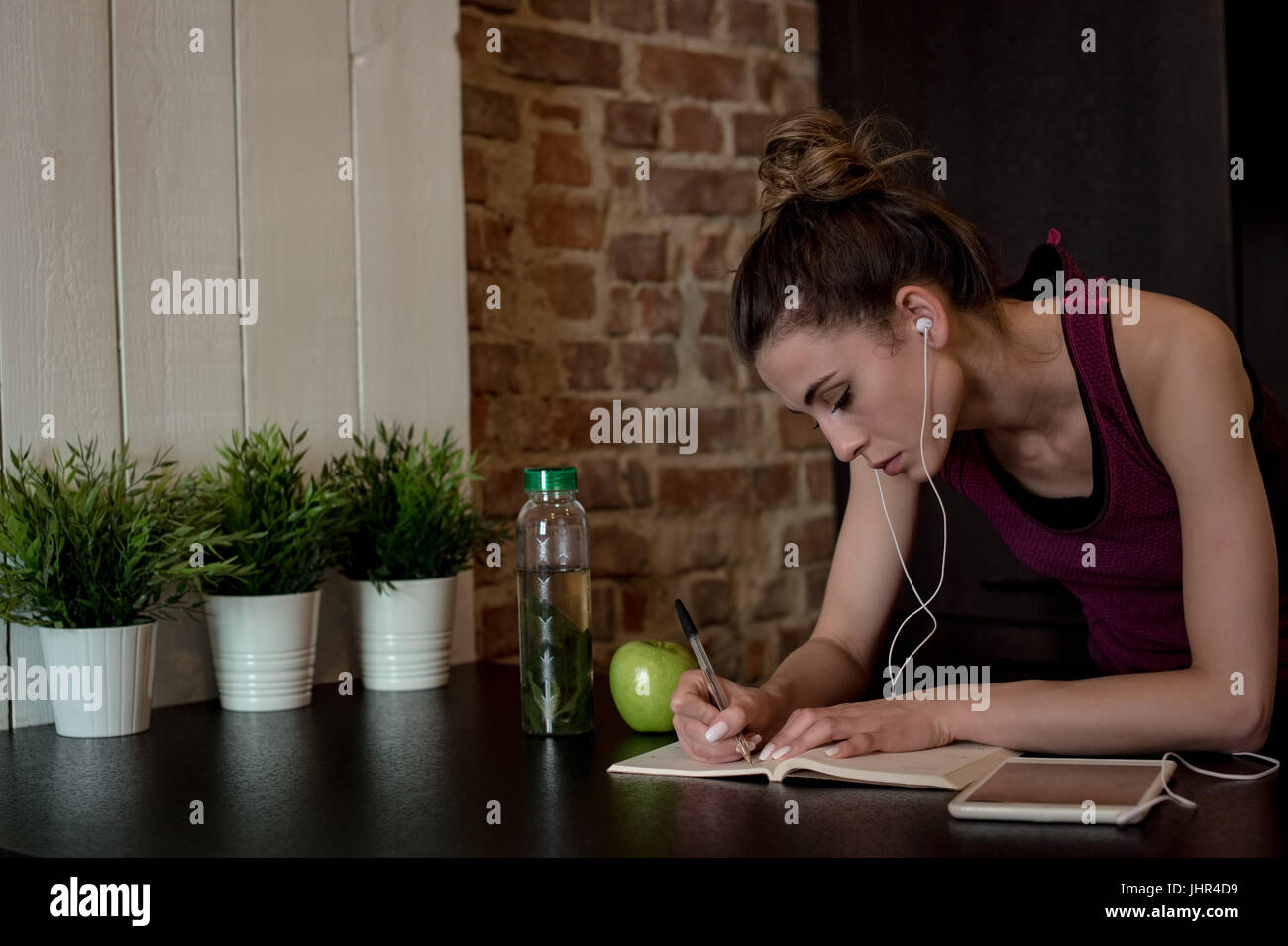 Beautiful woman writing in diary while listening to music on digital ...