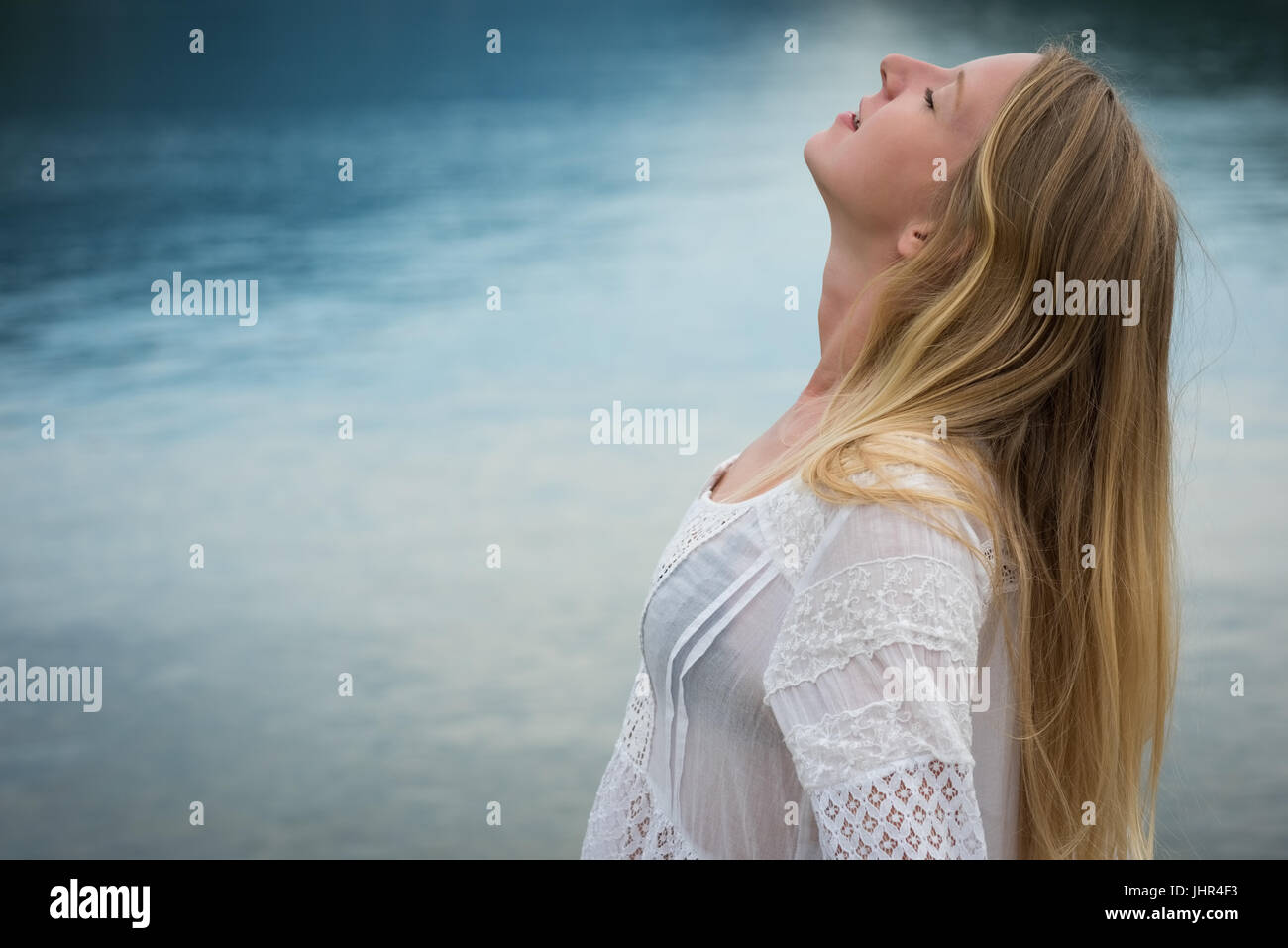 Profile view of woman with eyes closed at lakeshore Stock Photo - Alamy