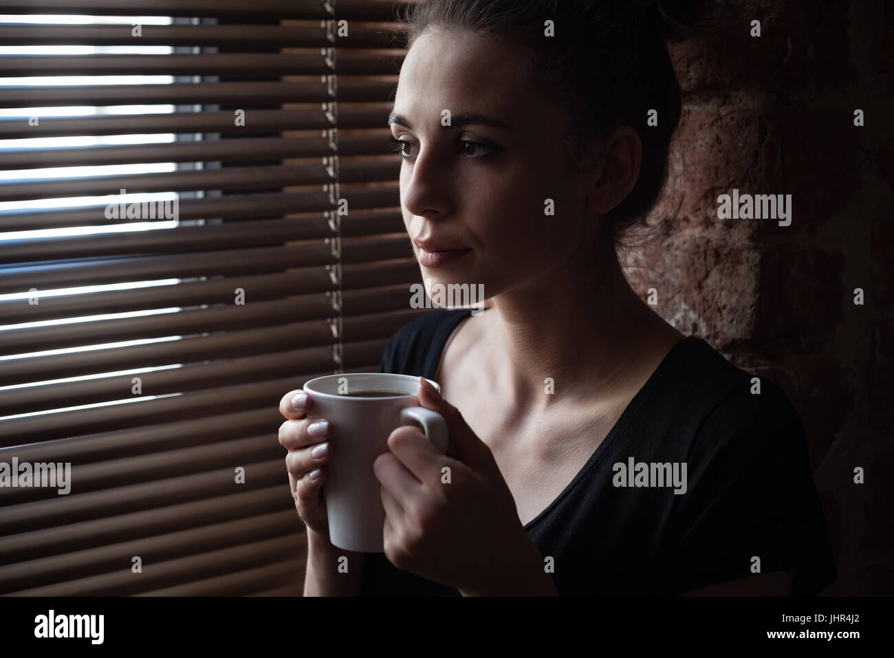 Beautiful woman having coffee near window at home Stock Photo - Alamy