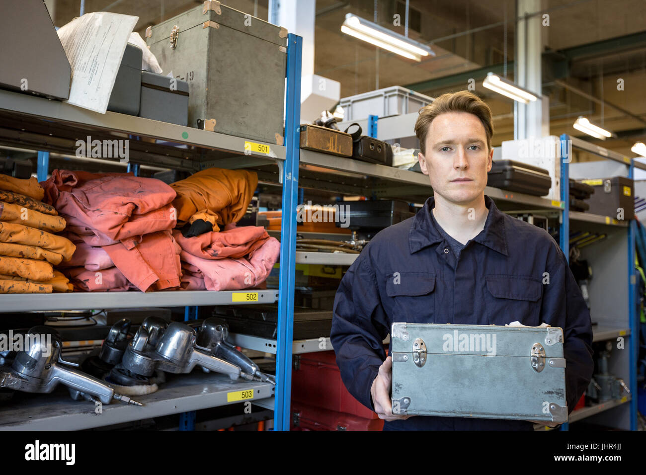 Portrait of male aircraft maintenance engineer holding a tool kit at ...