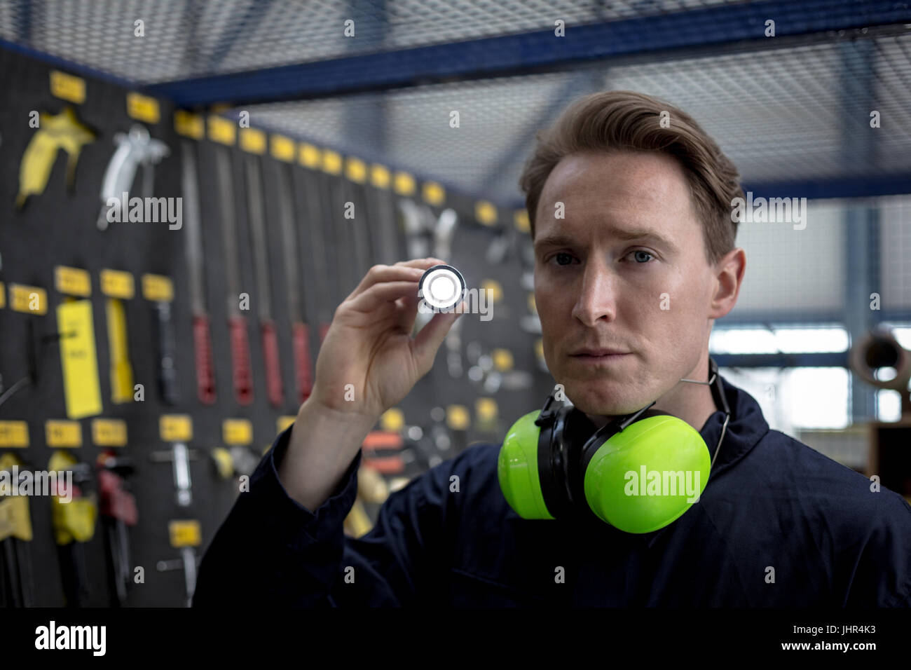 Portrait of male aircraft maintenance engineer holding a torch at ...