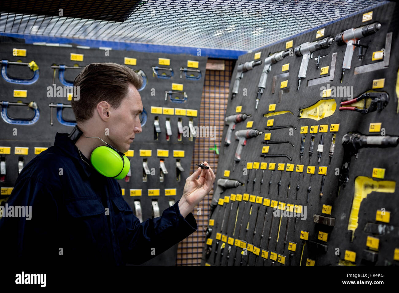 Male aircraft maintenance engineer examining various work tool at airlines maintenance facility ...