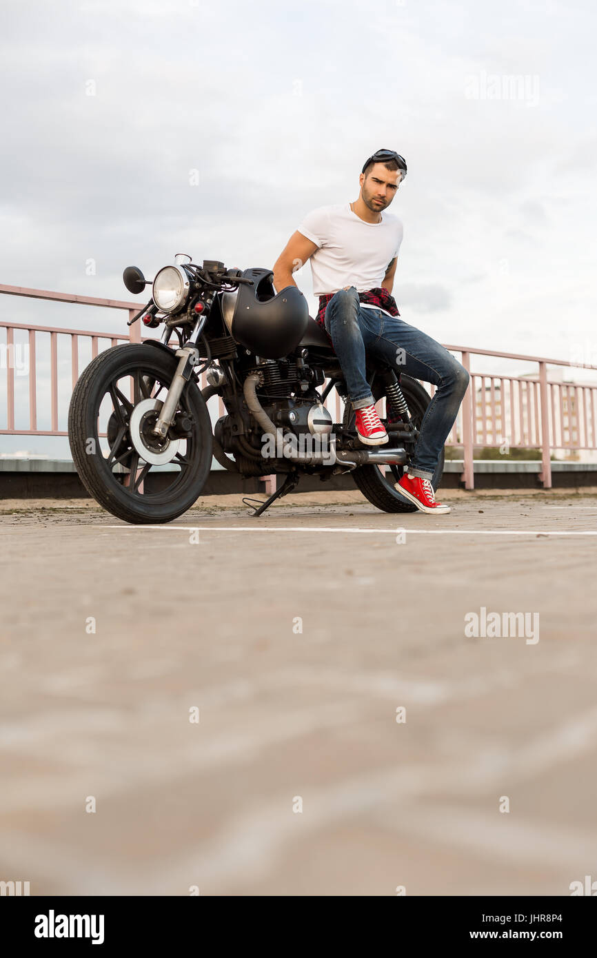 Handsome rider man with beard and mustache in red sneakers sit on ...