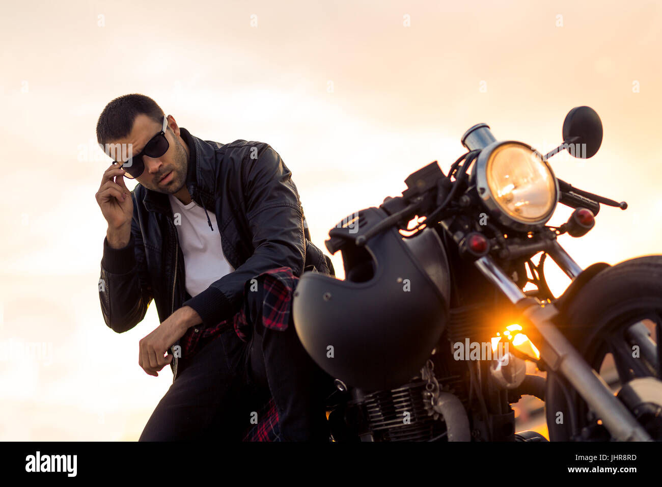 Handsome rider guy with beard and mustache in black biker jacket put on ...