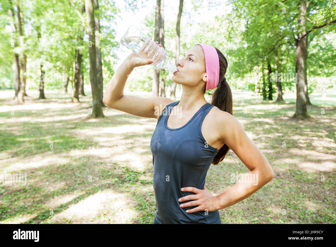 Fit sporty woman refreshing by bottle of water in nature healthy ...